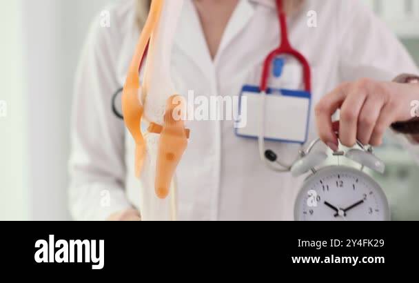 Knee joint and alarm clock in the hands of a traumatologist. Time to ...