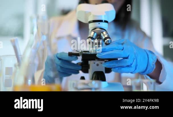 Scientist biologist virologist using microscope places petri dish for ...