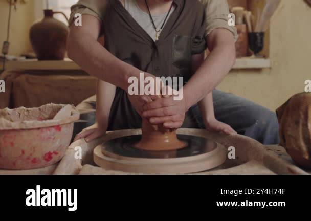 A father and child are bonding while shaping clay on a pottery wheel in ...