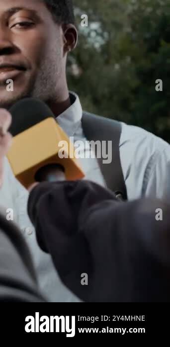 Vertical shot of Black male police officer being interviewed by press ...