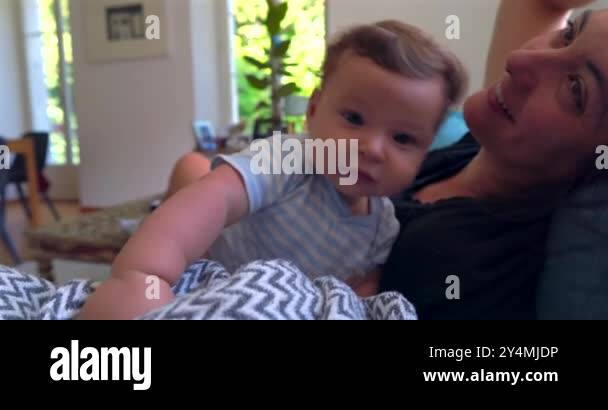 Baby staring curiously at the camera while lying on a soft blanket ...