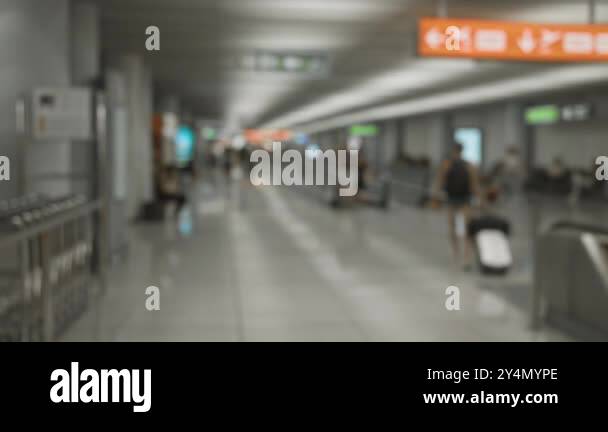 Blurred view of people moving through an airport terminal with signs ...