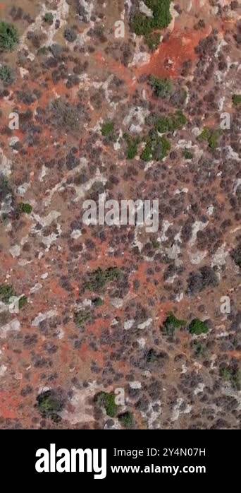 Panning across a vibrant red desert landscape reveals a winding dirt ...