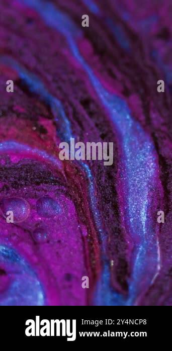 Vertical video. Glitter paint spill. Oil fluid flow. Defocused purple ...