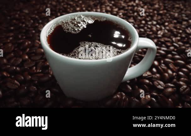 Close up of coffee bean drop in to hot espresso with pile of coffee ...