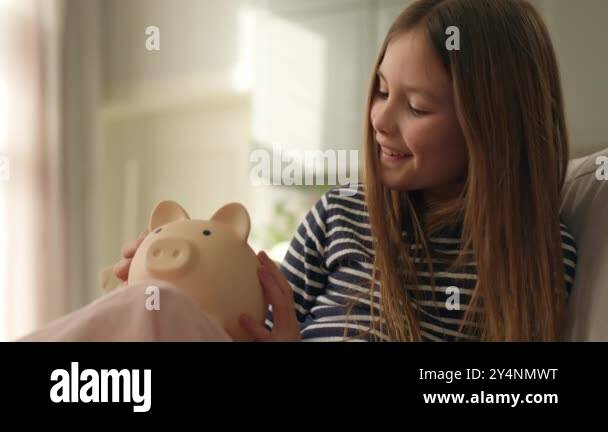 Happy little girl child kid daughter putting coins pennies in piggy ...