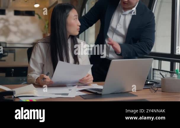 Two Asian business colleagues office partnership teamwork cooperation ...