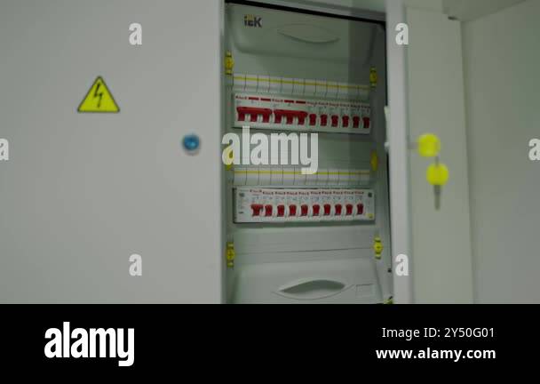 Open electrical cabinet in an industrial setting with safety signage ...