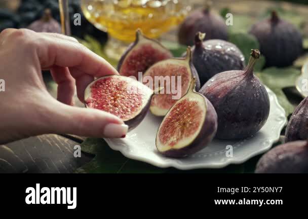 Woman takes fresh ripe fig slice from plate. Harvest serving with ...