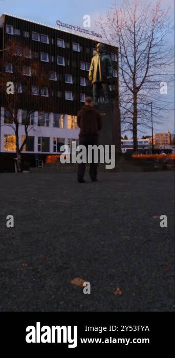 Man walking slowly towards Roald Amundsen statue in Tromso, Norway ...