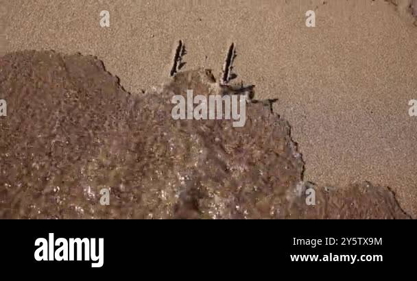 Sad emoticon drawn on sand washes away with sea wave. Bad mood ...