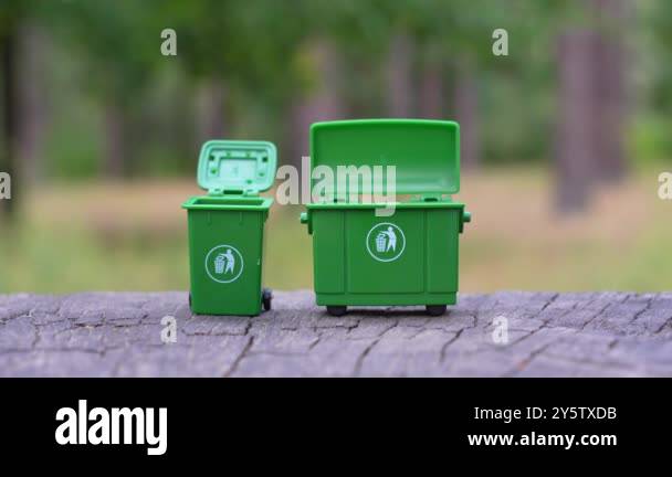 Close-up shot of two green toy trash bins set on a tree stump in the ...