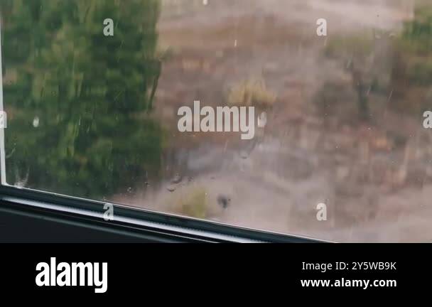 Soothing slow motion footage of rain falling on a window, with a ...