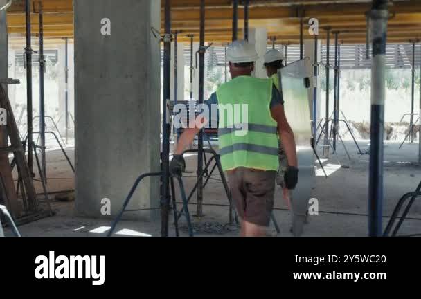 Construction Workers Carrying Material in Building Framework. Two ...