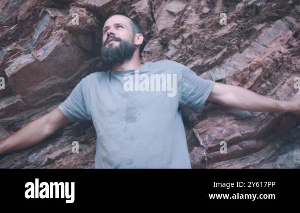 A young man climbs a dangerous path on a cliff to see a beautiful view ...
