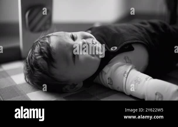 Black and white close-up of a baby lying on their back, showing early ...