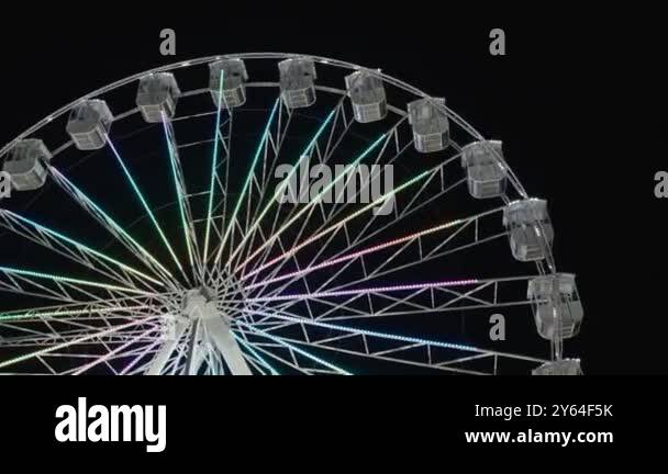 A colorful Ferris wheel rotates against a night sky. Enjoy the vibrant ...