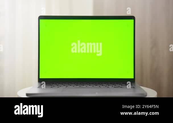 Fly in Laptop with green screen on a table in a minimalist interior ...