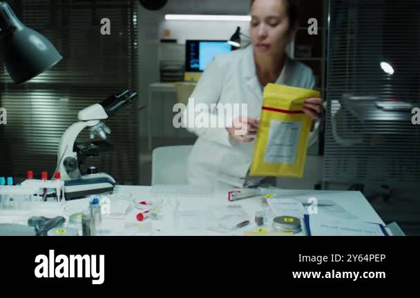 Female forensic scientist walking in crime lab, sitting at desk with ...
