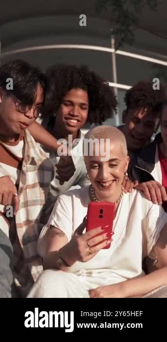 Group of young gen z friends sitting together using cell phone to share ...