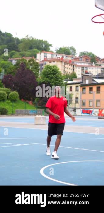Vertical video of a basketball player throwing a ball in an outdoor ...