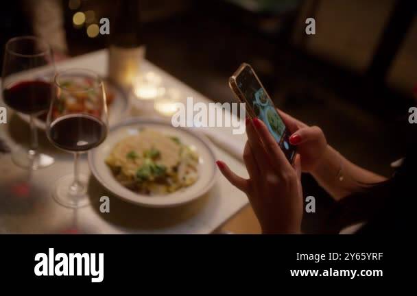 A woman captures the aesthetics of her dinner with a camera during a ...