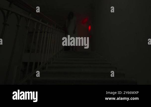 Young female on stairway in darkness. Creepy ghost woman in white dress ...