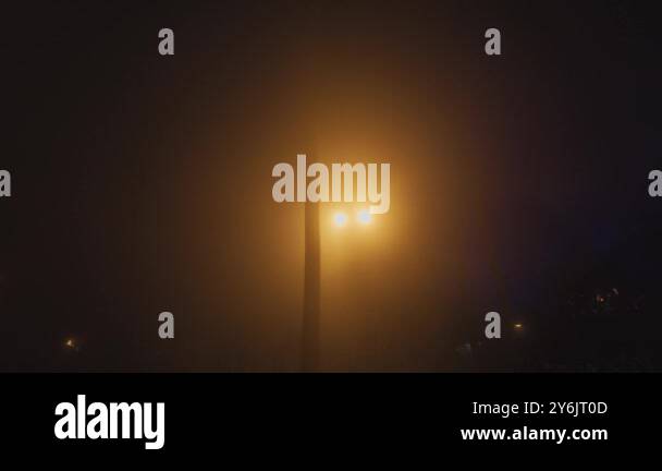 A dimly lit scene shrouded in fog, featuring a tall pole with two ...