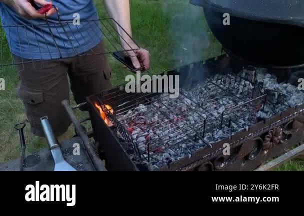 A handsome white man prepares food on a grill in a backyard, enjoying ...