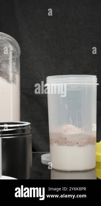 Vertical video. Athlete pouring Protein Powder into a shaker bottle ...