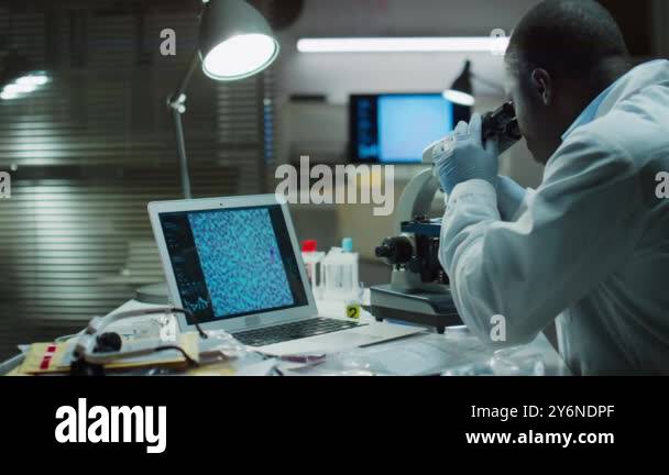 Black forensic scientist wearing gloves examining trace evidence under ...