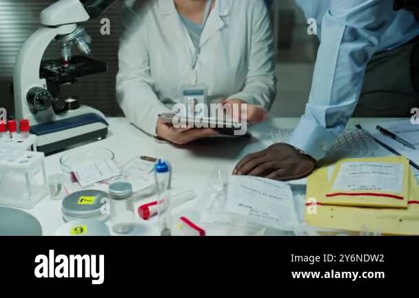 Tilt up shot of female forensic scientist commenting on evidence test ...