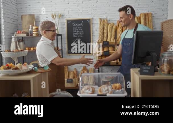 Woman and man smiling and shaking hands in bakery with pastries and ...