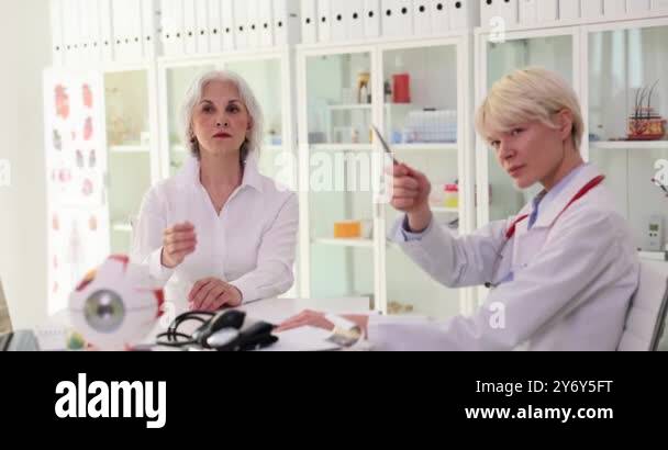 Female doctor points to Snellen chart to check patient vision. Doctor ...