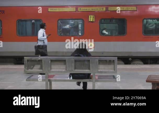 isolated girl sitting at iron bench to catch the train at evening with ...