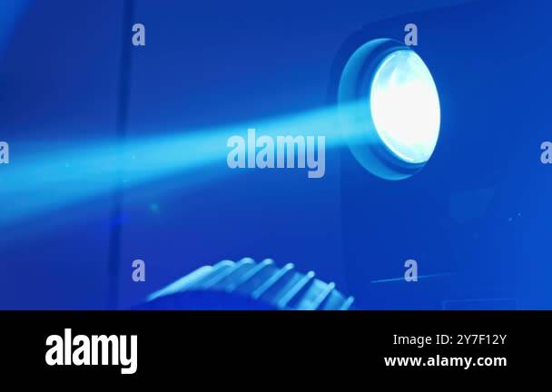 A brilliant blue spotlight shines its focused beam through a dark room ...