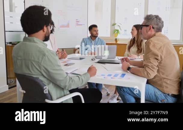 A lively team discussion unfolds in a modern office, where diverse colleagues share ideas with ...