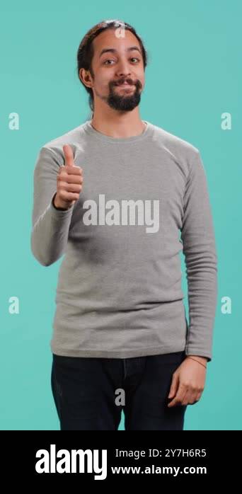 Vertical video Cheerful man showing thumbs up sign gesturing, exulting ...