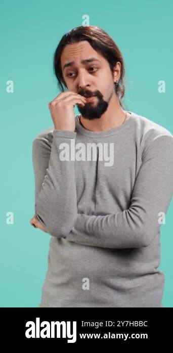 Vertical video Distraught man biting nails, being afraid of receiving ...