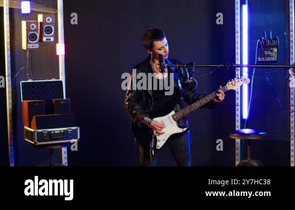 Confident female rocker performing live with a bass guitar on stage ...