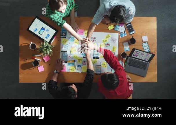 Top view of skilled team putting hand together to celebrate at meeting table while brainstorm ...