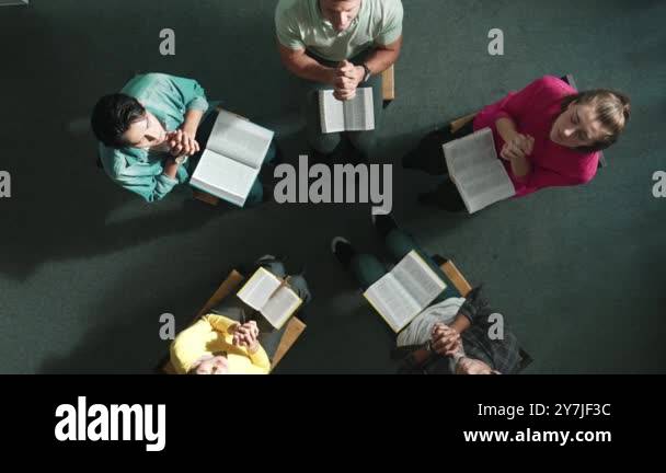 Top down view of prayers reading bible with cross on the laps while ...