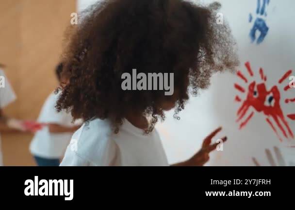 Diverse student touch hands with color at stained wall in art lesson ...