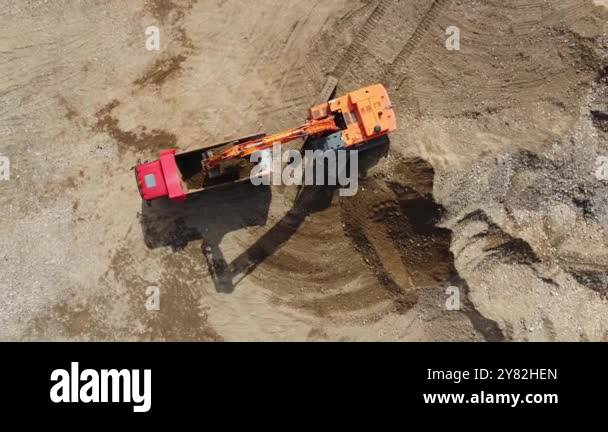 Excavator loading sand into dump truck at construction site near river ...