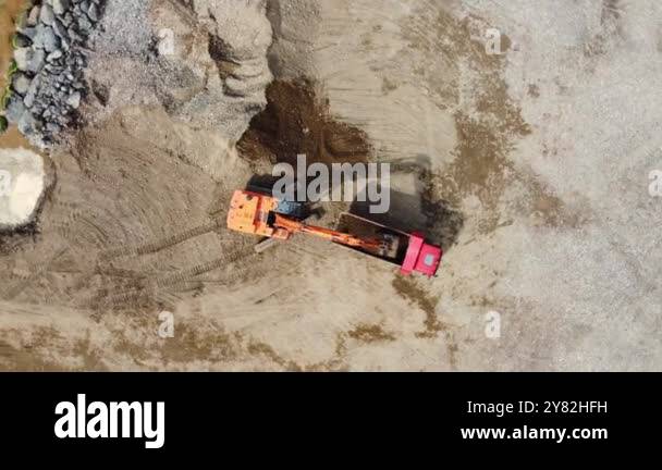 Excavator loading sand into dump truck at construction site near river ...