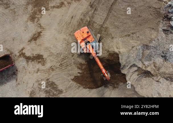 Excavator loading sand into dump truck at construction site near river ...