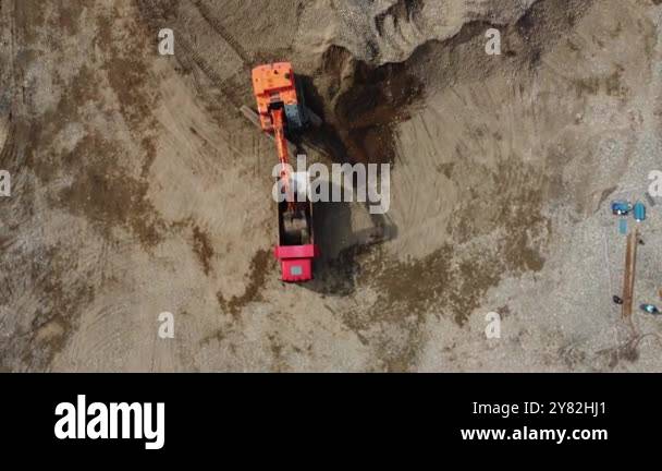 Excavator loading sand into dump truck at construction site near river ...