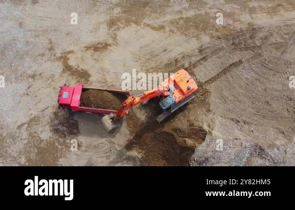Excavator loading sand into dump truck at construction site near river ...