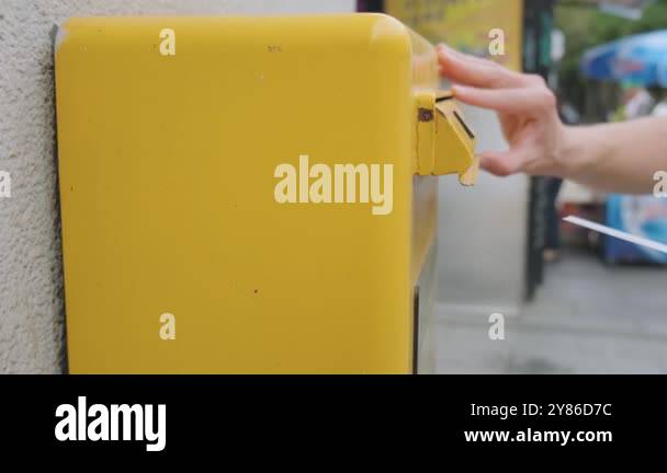 Man tourist sending letter into a yellow street mailbox. Male drops a ...