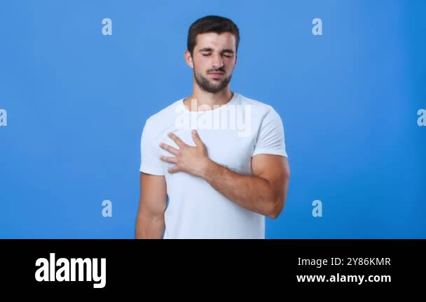 A young man stands with one hand on his chest, showing a thoughtful ...